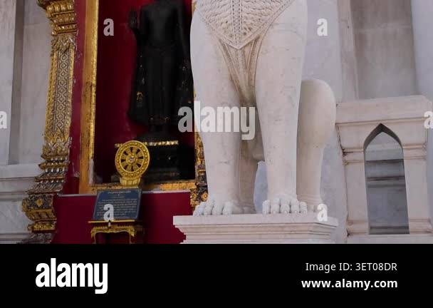 White guardian lion statue fronting temple niche with black buddha ...
