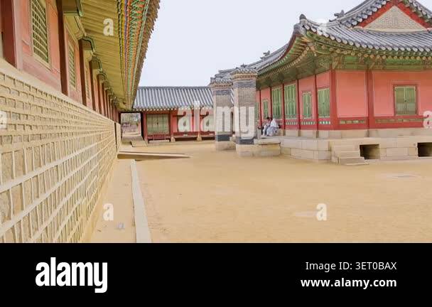 Palace courtyard with asian couple strolling hanbok, long stone wall ...