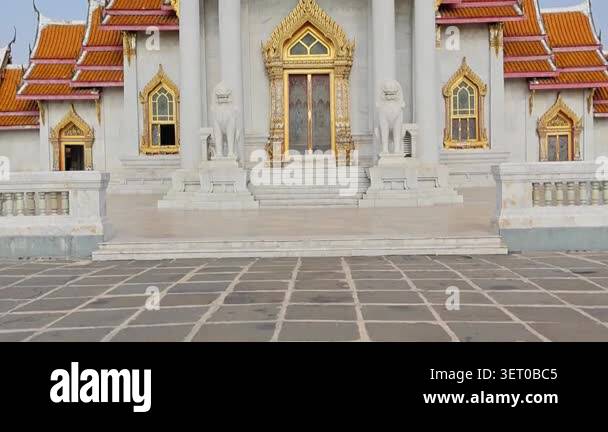 Ornate Thai temple facade with golden door, wide marble courtyard with ...