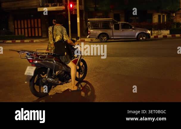 Motorcyclist asian stopped at city intersection under streetlights ...