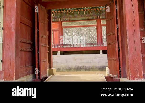 Open wooden gate framing ornate inner wall with lattice panels, stone ...