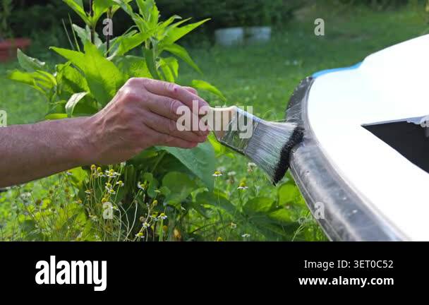 Close up of a worker's hand holding a paintbrush, meticulously applying ...