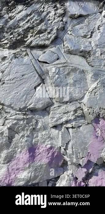 Close-up vertical shot of an industrial stone wall coated in metallic ...