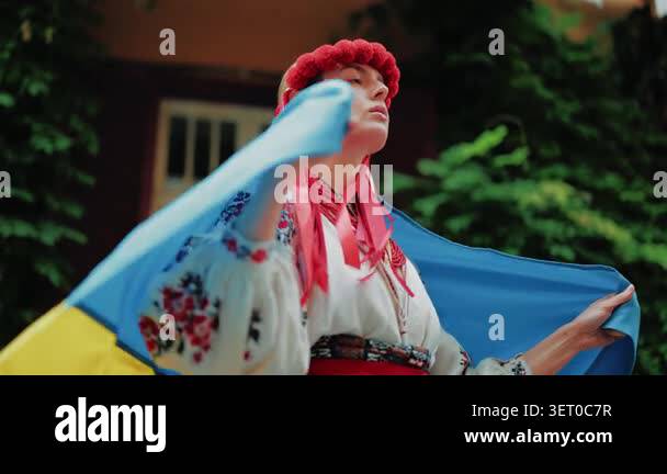 Woman in a traditional vyshyvanka and red floral wreath poses while ...