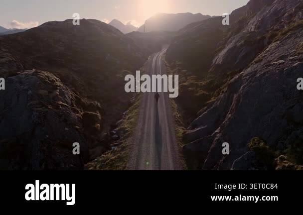Aerial view of a solitary person walking beside a narrow road through ...