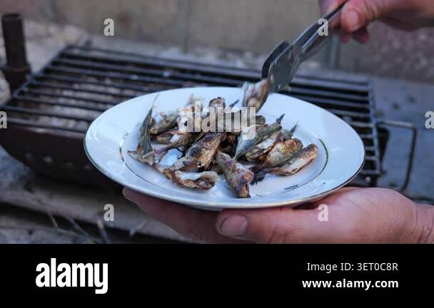 Male hands holding a white plate while using metal tongs to collect ...