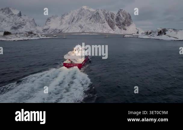 A white passenger boat travels across dark cold water, leaving a wide ...