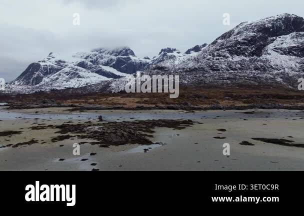 Low-angle wide view of a snow-flecked mountain range rising behind a ...