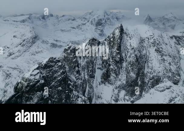 Mid-to-long aerial shot of a rugged alpine ridge with steep rocky ...