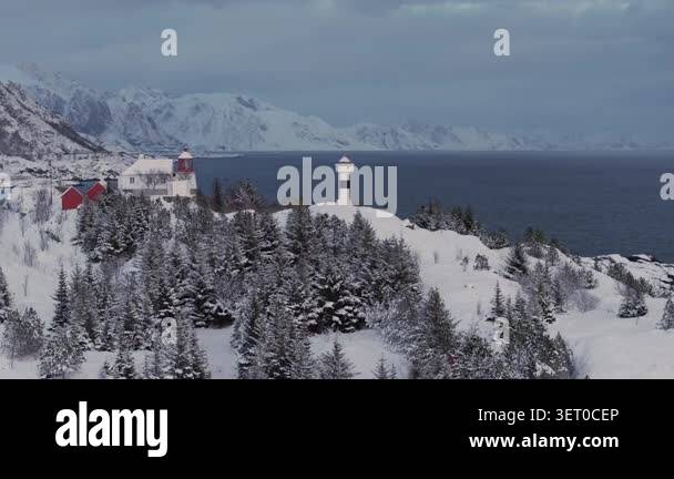 A snow-covered rocky promontory juts into a dark calm sea beneath an ...