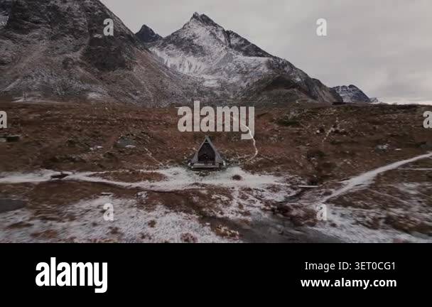 Small wooden A-frame cabin sits in the lower third of a wide ...