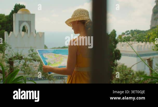Female tourist in summer dress reading map above Capri coastline on ...