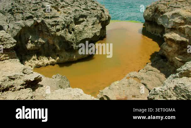 Natural tidal pool surrounded by large rocks and ocean water at Angel ...
