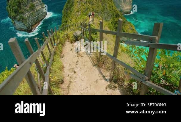 Wooden railing borders dangerous hiking path on cliff overlooking blue ...