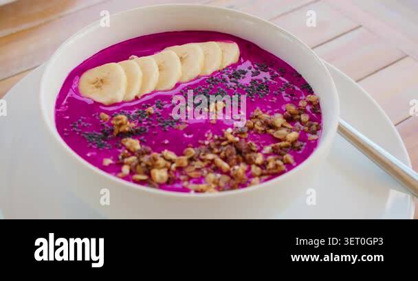 Vibrant pink dragon fruit smoothie bowl topped with banana slices ...