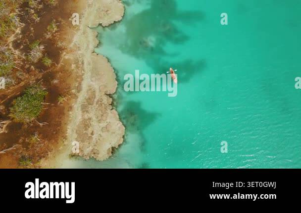 Couple kayaking on turquoise water near rocky shore of Bacalar lake in ...