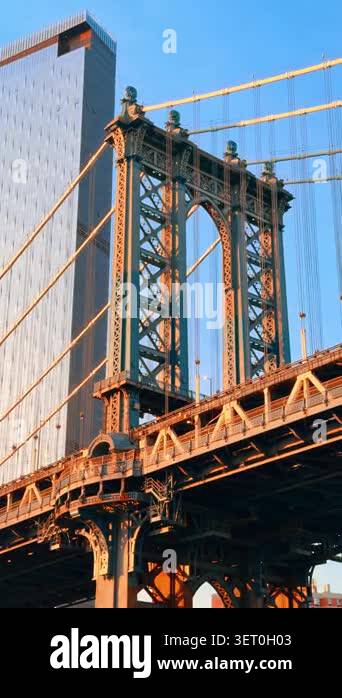 The iconic Manhattan Bridge in the light of setting sun. Moving under ...