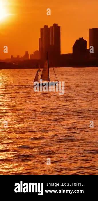 Sailboats on the riverscape colored orange at sunset time. Water sport ...