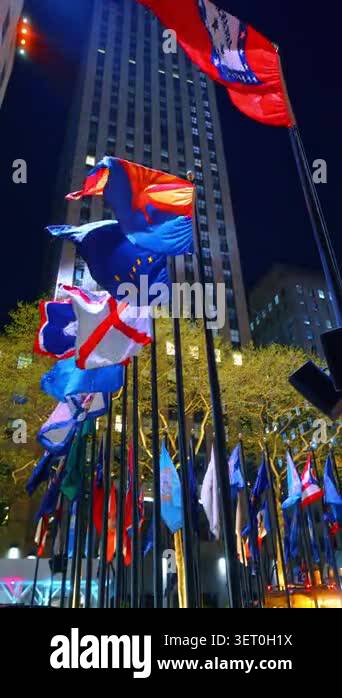 Flags waving outside a skyscraper at night, New York City, Upward low ...
