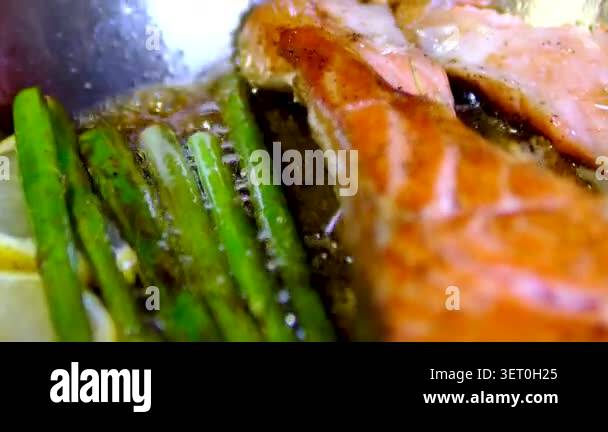 Chef in black gloves seasons salmon, sears it on a stainless steel pan ...
