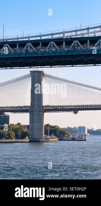 Long train goes by the Manhattan Bridge. Flow of cars moves by the ...