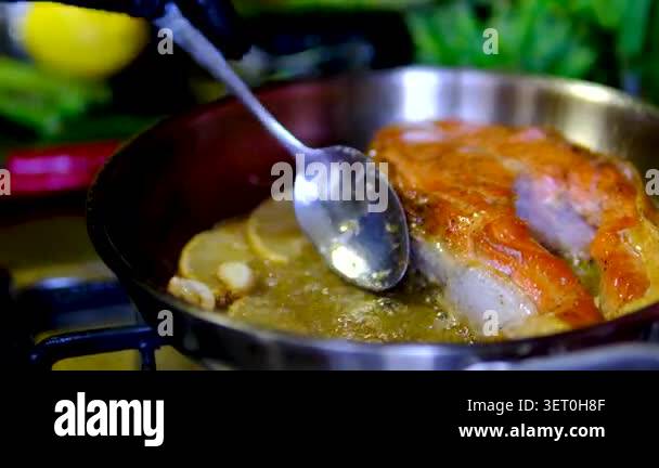 Chef in black gloves seasons salmon, sears it on a stainless steel pan ...