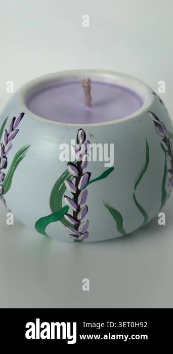 Close up of handmade lavender soy wax candle spinning, painted plaster ...