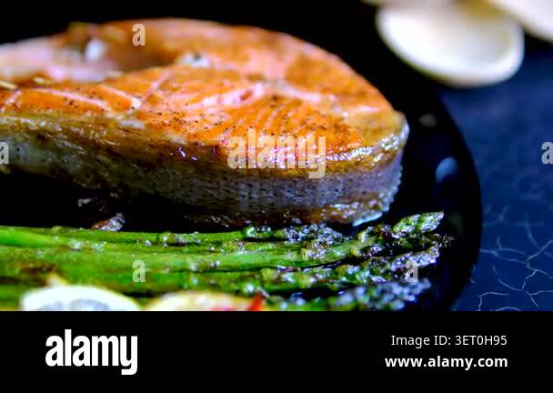 Chef in black gloves seasons salmon, sears it on a stainless steel pan ...