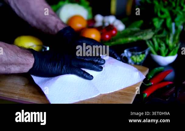 Chef in black gloves seasons salmon, sears it on a stainless steel pan ...