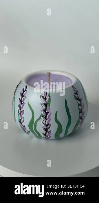 Handmade lavender soy candle in painted plaster pot rotating close up ...