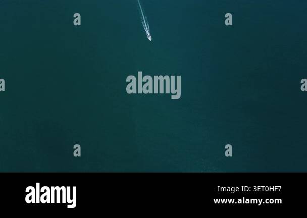 Aerial drone captures a small boat crossing calm open blue water near ...