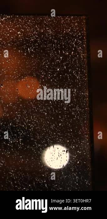 Rainy city night view through wet glass with glowing lights. High ...