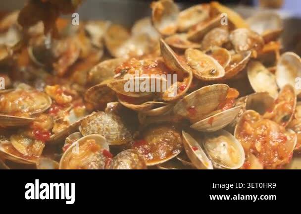 Steamed clams in marinara sauce served in warm restaurant evening light ...