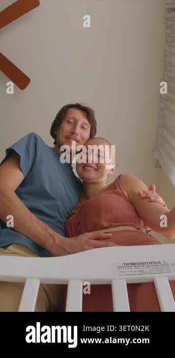 Smiling mother and father hugging and looking at their newborn in a ...