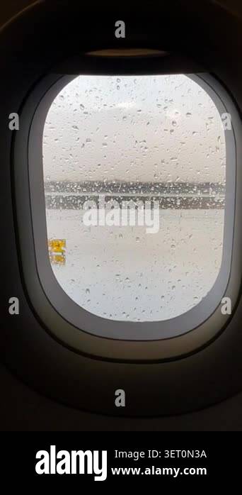 View through a passenger aircraft window covered with raindrops during ...