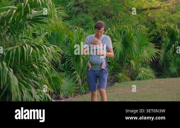 Father carries his three month old baby son in an ergonomic baby ...