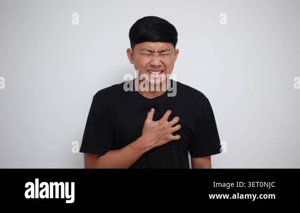 Asian man clutching his chest in severe pain, suffering from a sudden ...