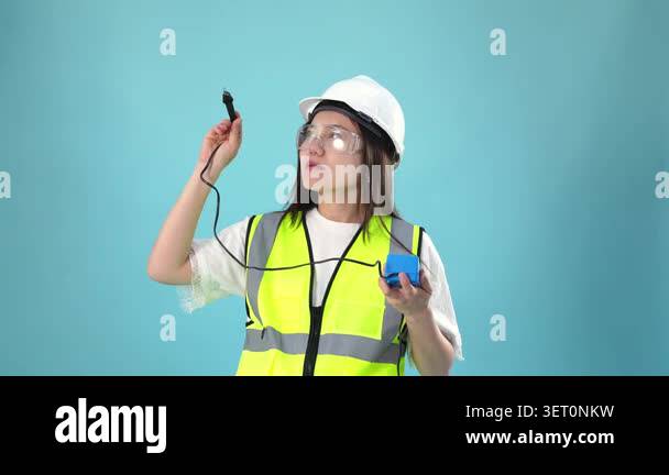 A young focused female worker in a hard hat holding and examining an ...