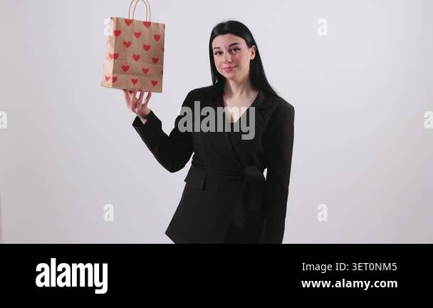 A elegant young female holds and points to a valentines day themed gift ...