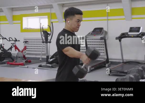 A strong little person exercises his shoulders by lifting a dumbbell in ...