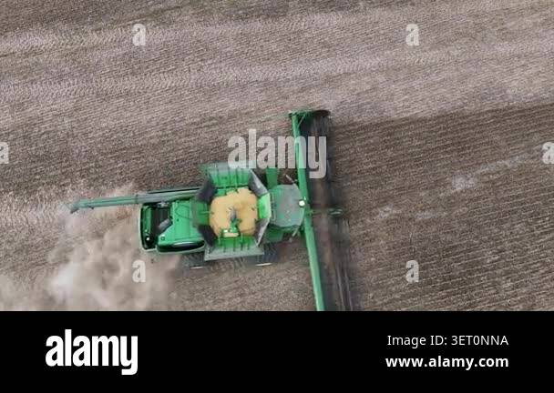 A top down drone shot captures a harvesting machine gathering crops on ...