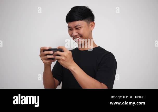 An energetic young Asian man intently playing a fast-paced game on his ...