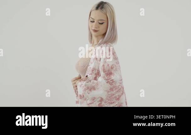 A charming female model turns around and smiles gently during a studio ...