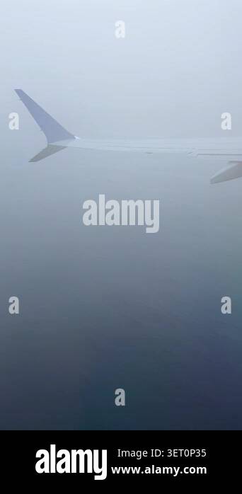 airplane wing over ocean viewed from passenger window during climb into ...
