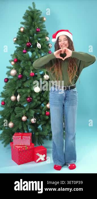 A cheerful female celebrating winter holidays and showing love sign by ...