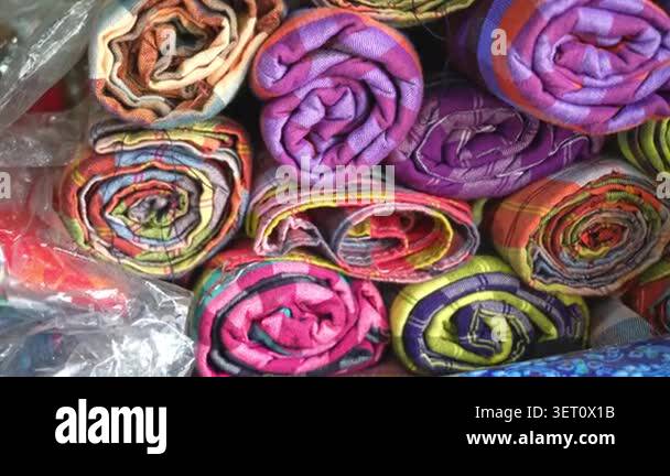 Close up of person choosing colorful woven loincloth fabric rolls in ...