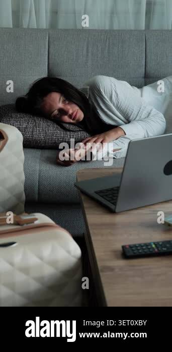 Digital nomad burnout and remote work fatigue. Woman lying on sofa near ...