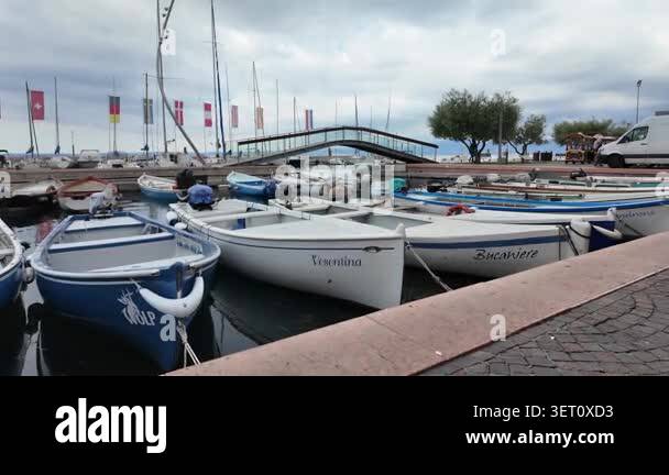 Bardolino, Italy - May 14, 2026 - Boats docked in a harbor with flags ...