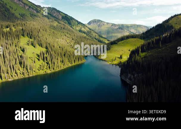 High angle aerial view of turquoise alpine lake surrounded by dense ...