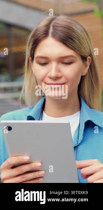 Close-up of beautiful girl smiling while using tablet in urban park ...
